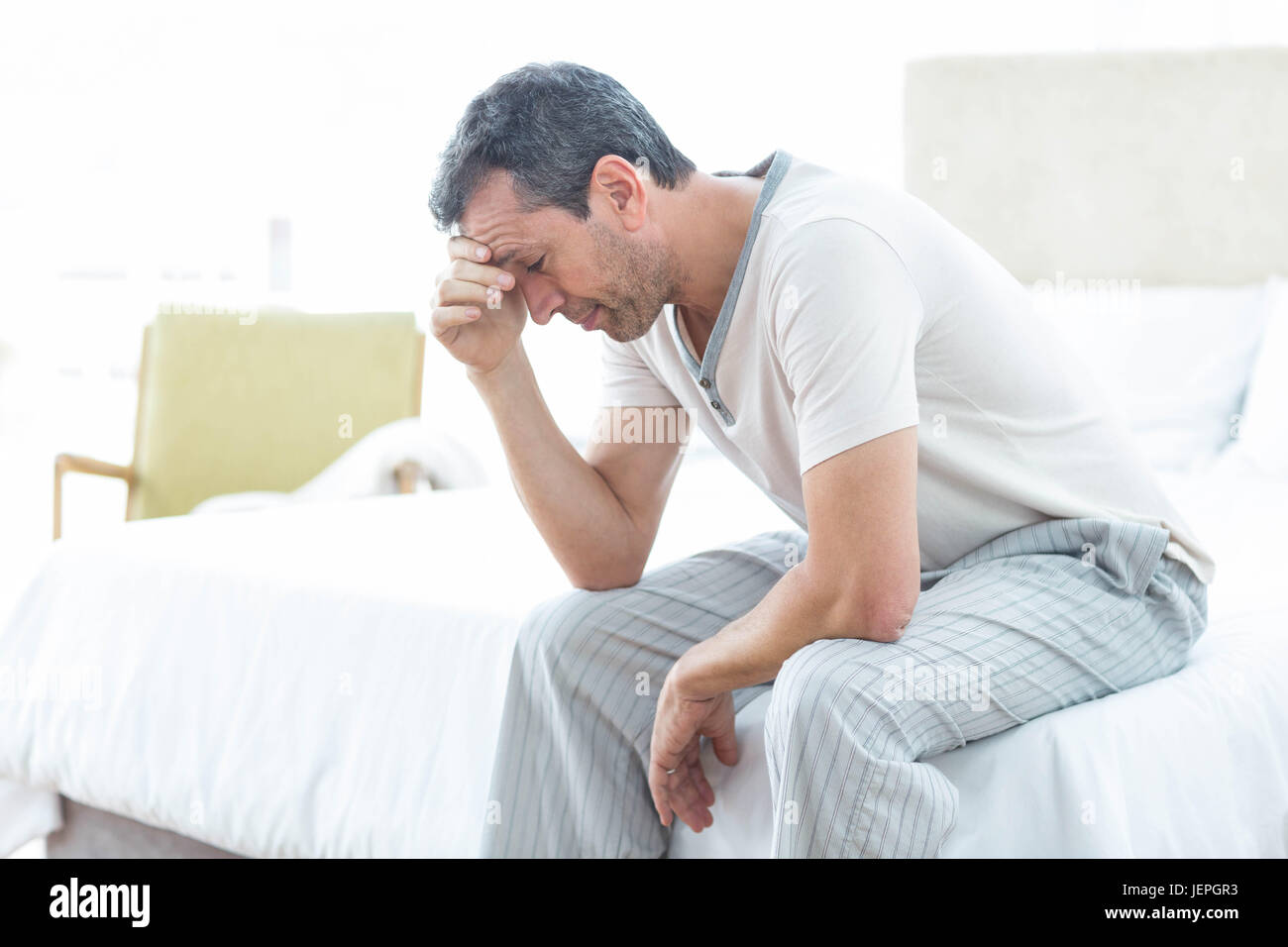 Worried man sitting on bed Stock Photo - Alamy