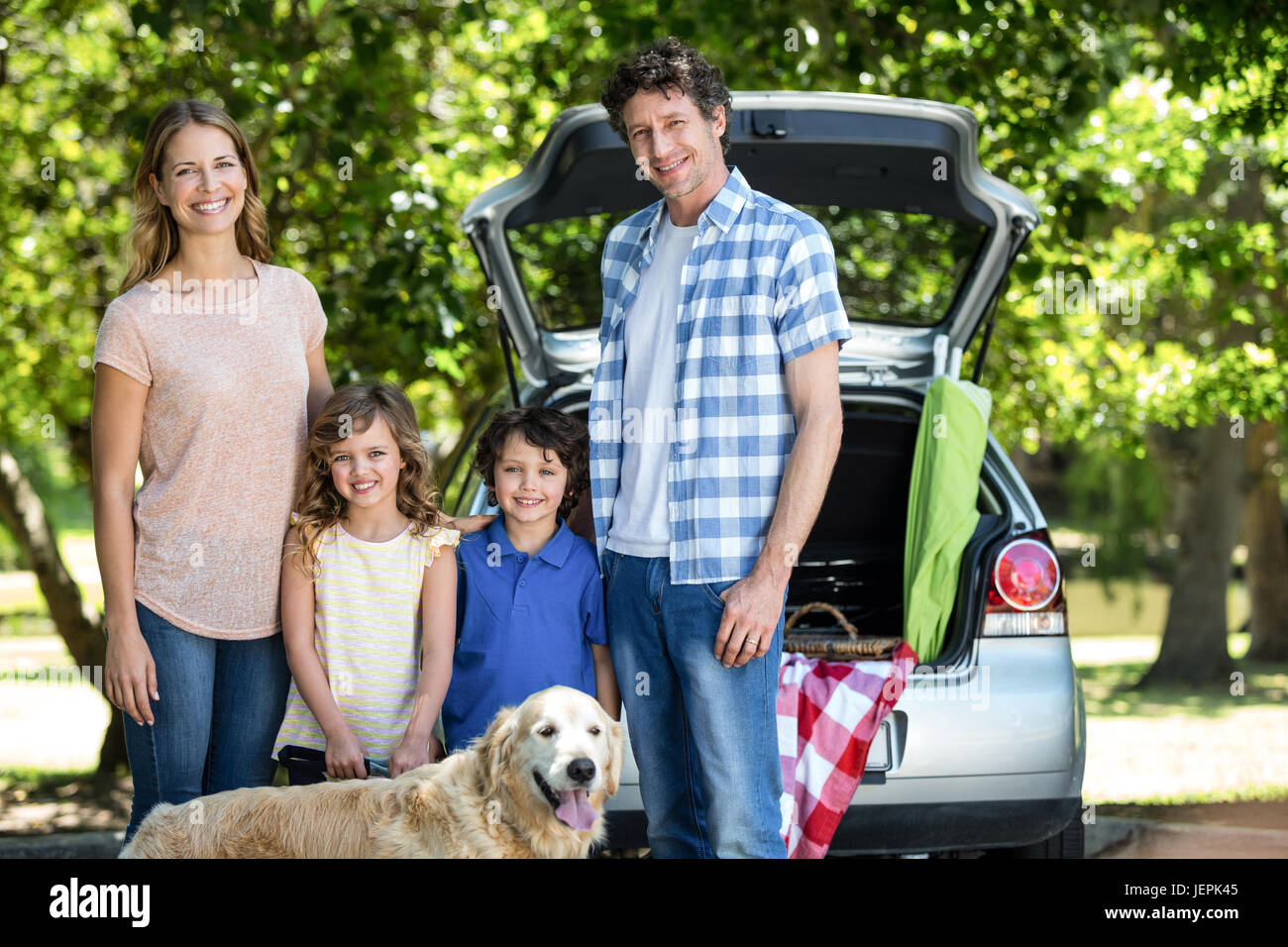 Smiling family standing in front of a car Stock Photo - Alamy