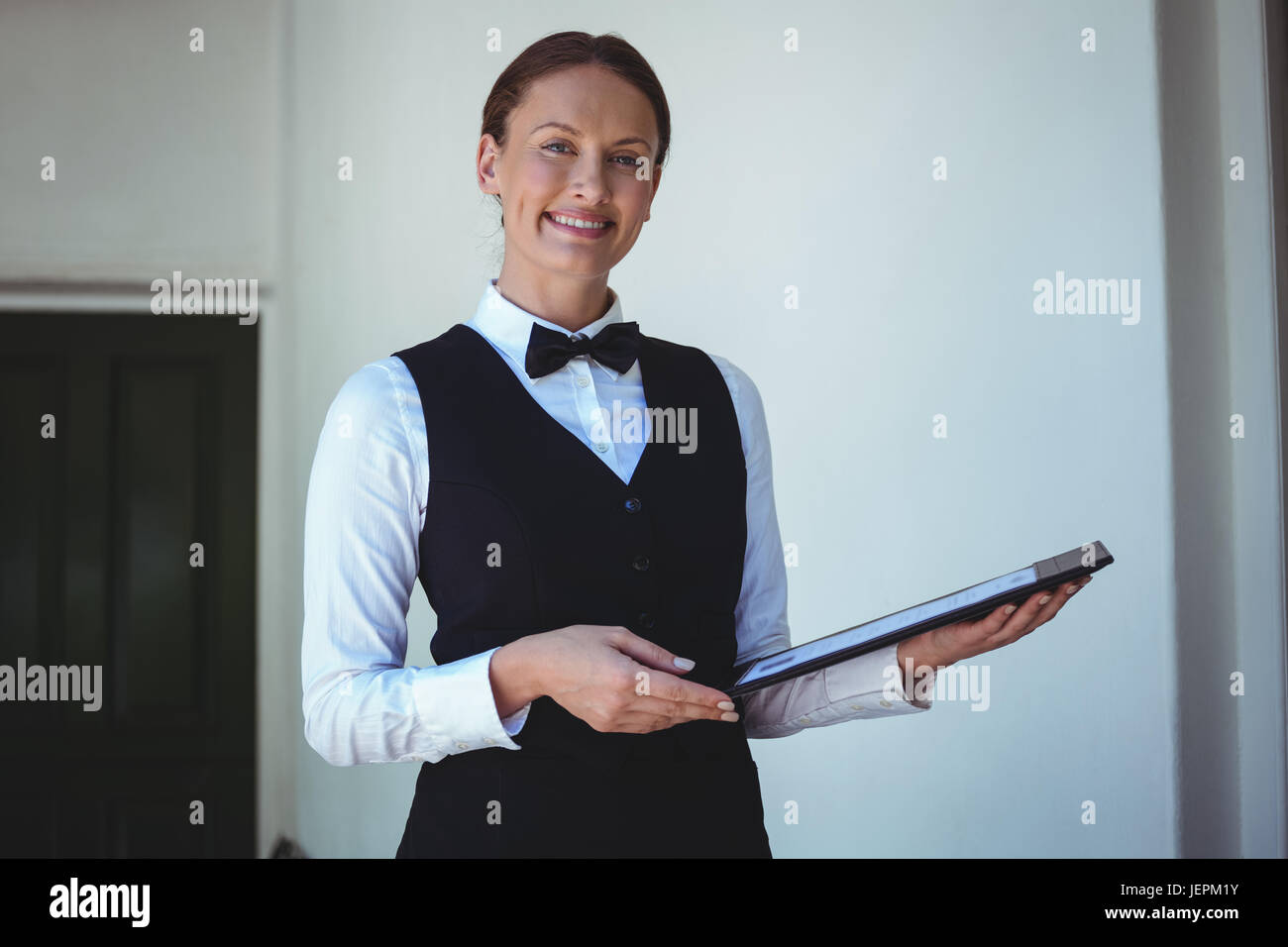 Smiling waitress holding a menu Stock Photo - Alamy