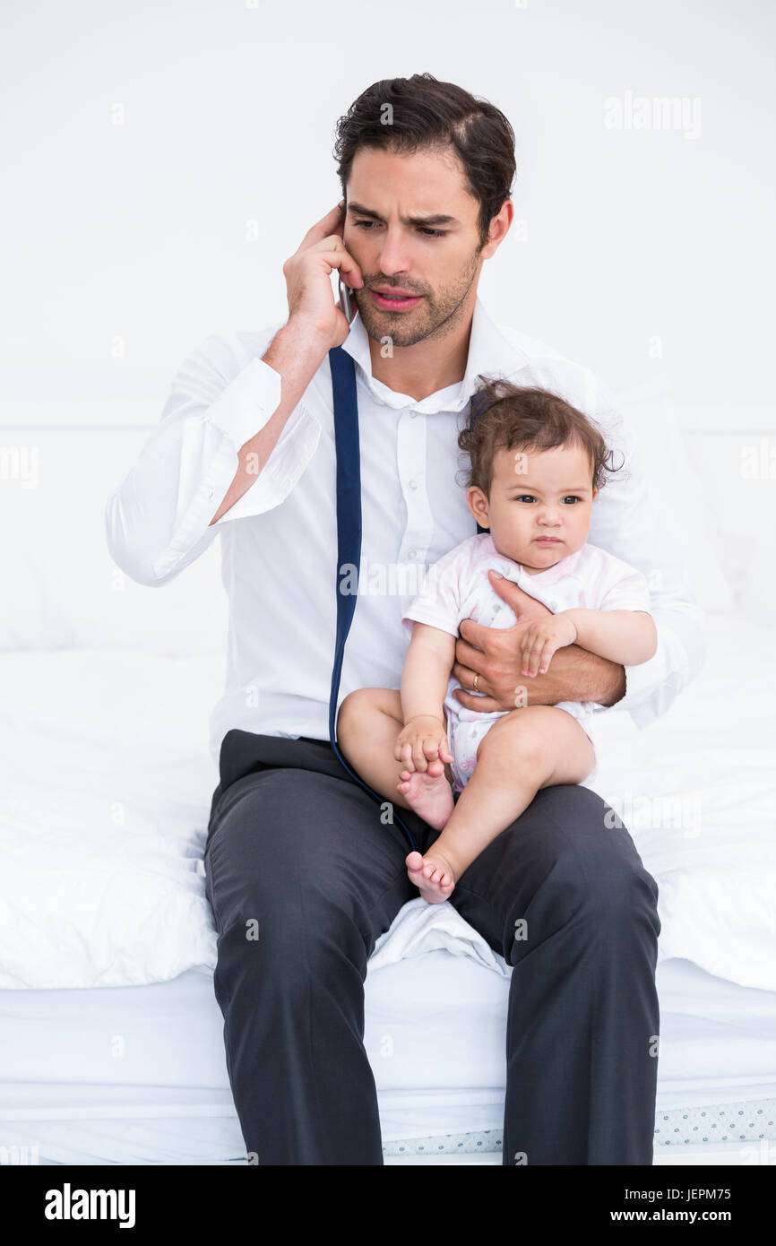 Father talking on mobile phone with baby Stock Photo - Alamy