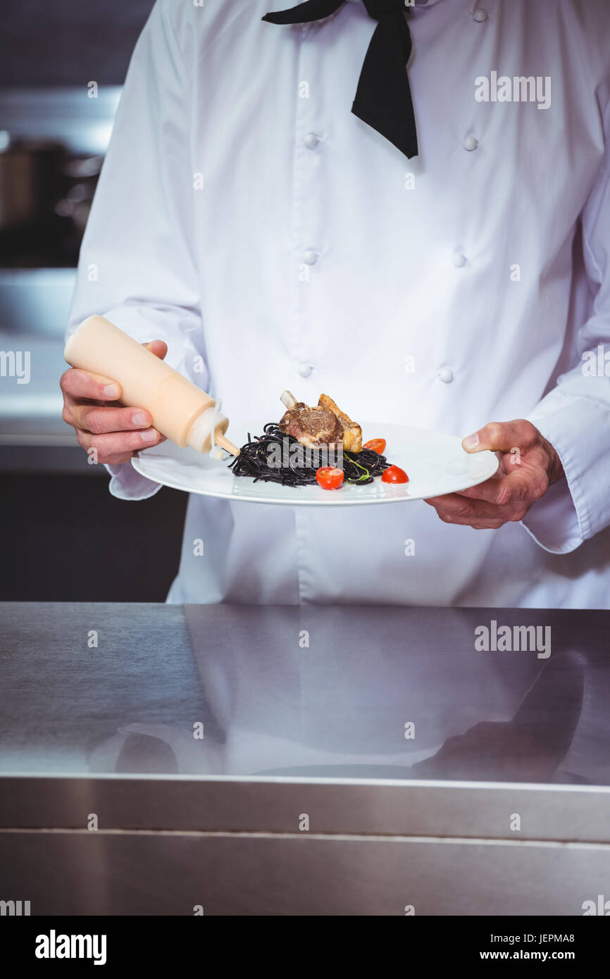 Chef putting sauce on a dish of spaghetti Stock Photo - Alamy