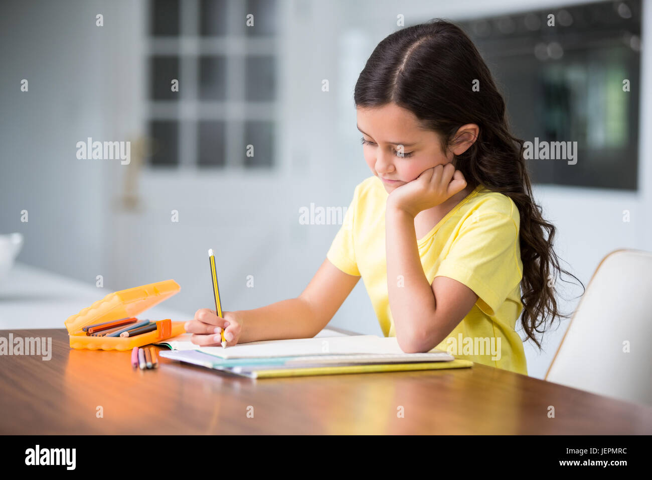 Girl studying while sitting at desk Stock Photo - Alamy