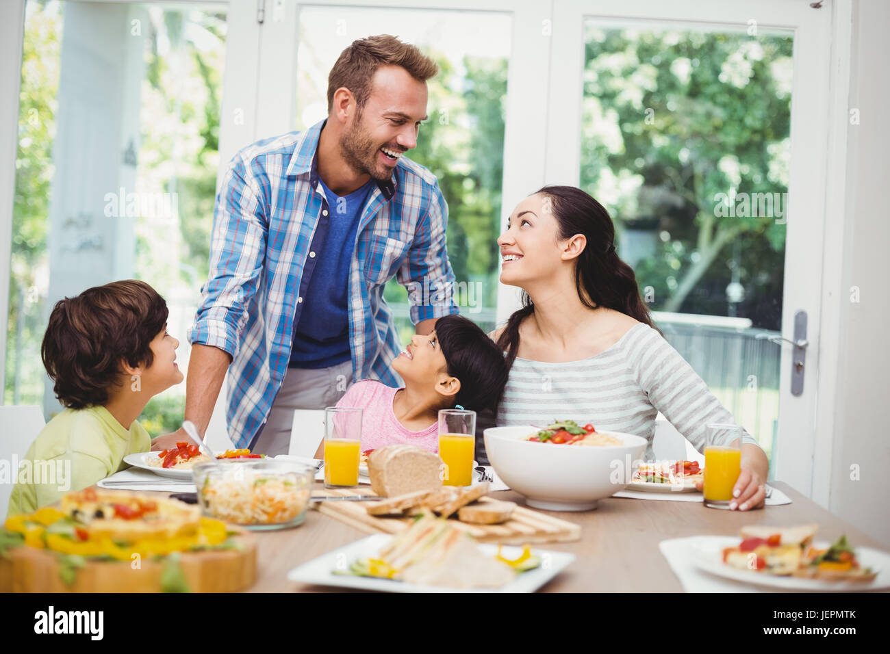 Smiling family discussing at dining table Stock Photo - Alamy