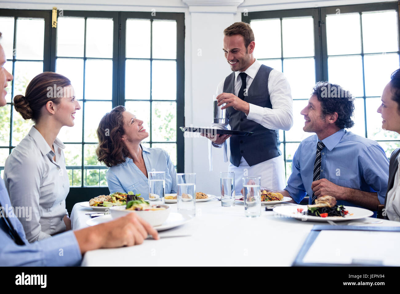 Waiter serving water to business people Stock Photo - Alamy