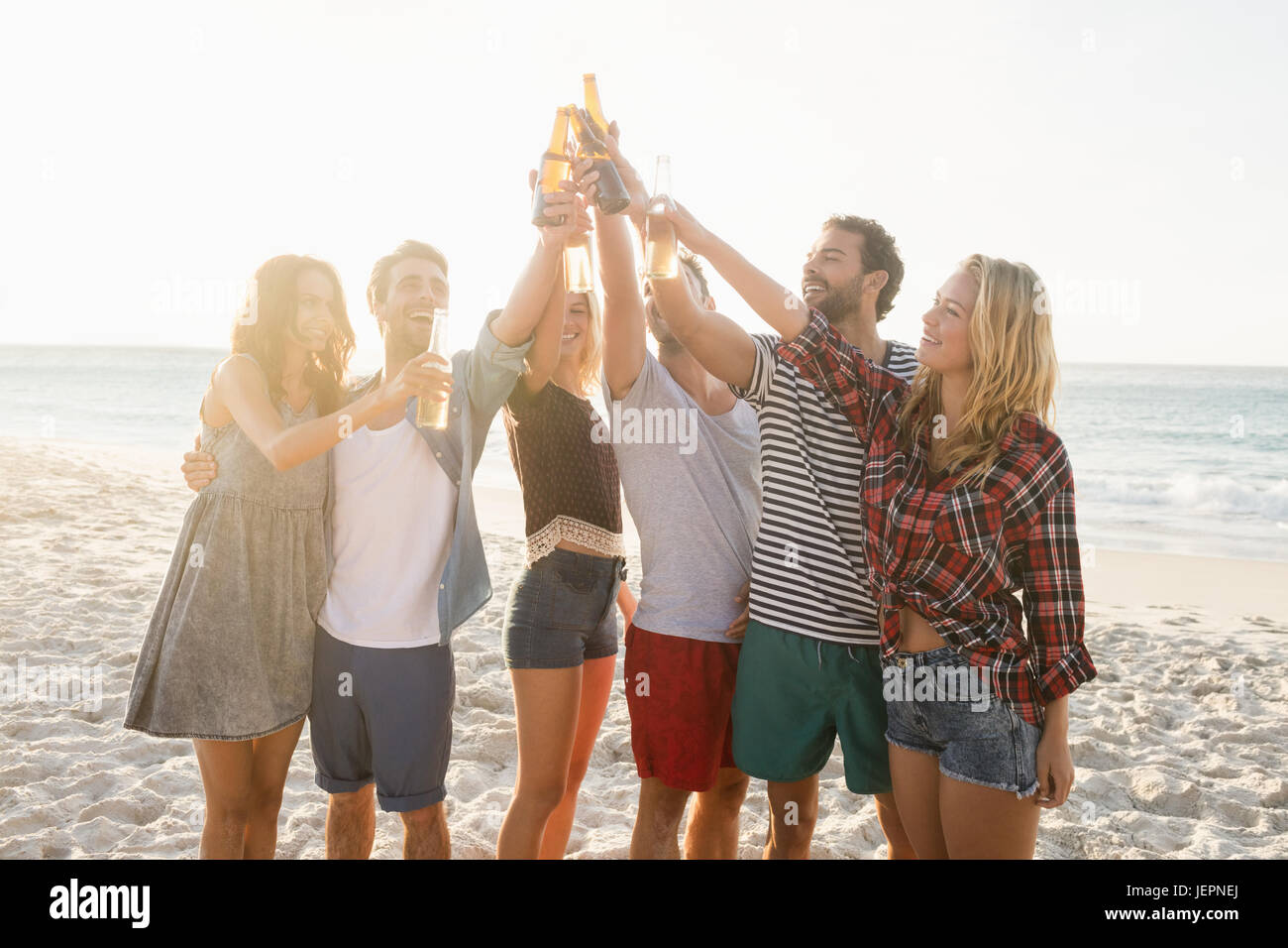 Happy friends raising beer bottles Stock Photo - Alamy