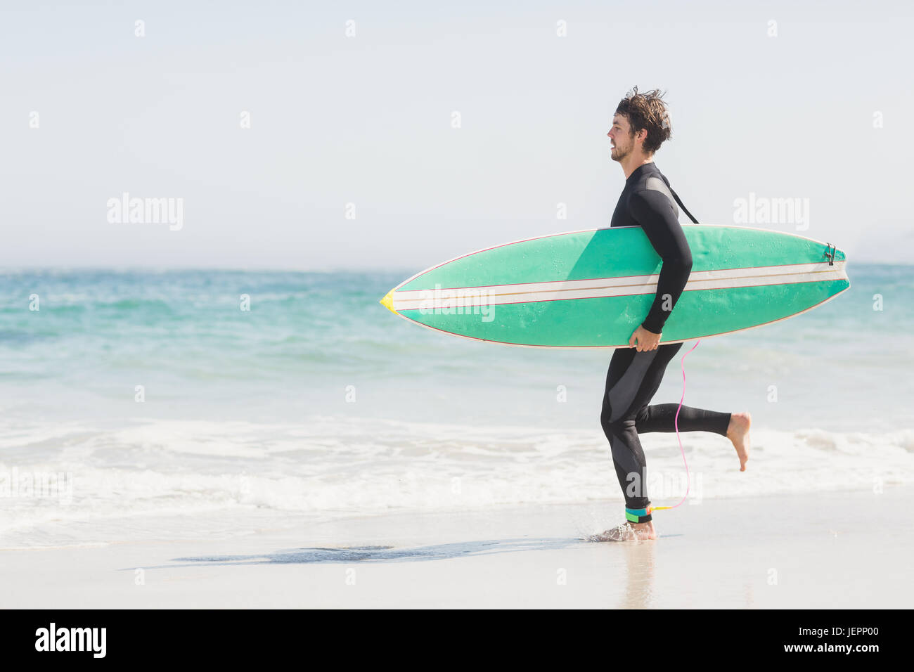 Man with surfboard running towards sea Stock Photo - Alamy