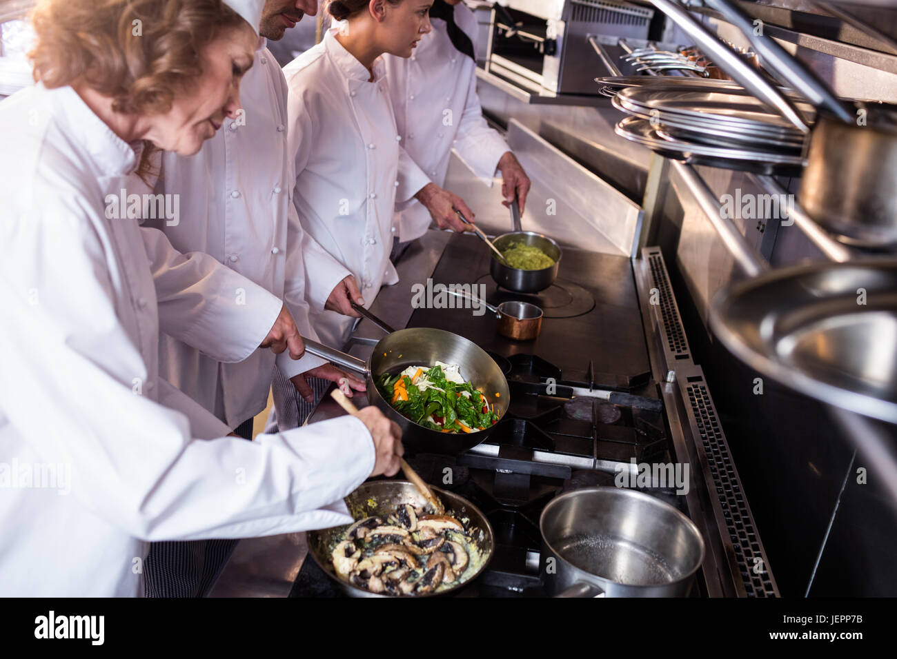 Group of chef preparing food in the kitchen Stock Photo - Alamy