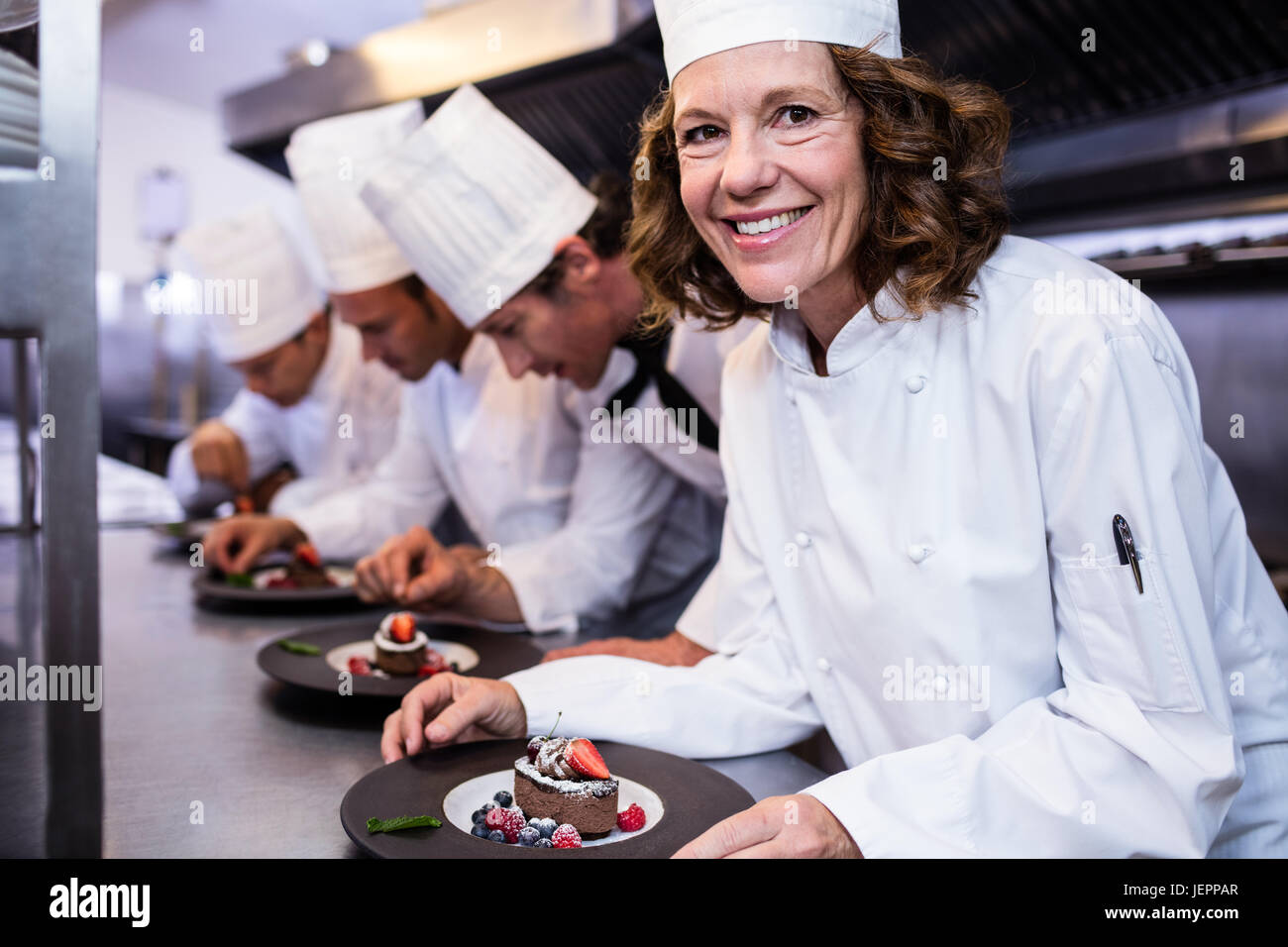 Chefs team finishing dessert plates Stock Photo - Alamy