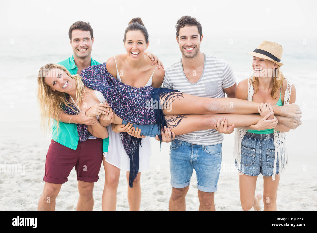 Group of friends lifting a woman Stock Photo - Alamy
