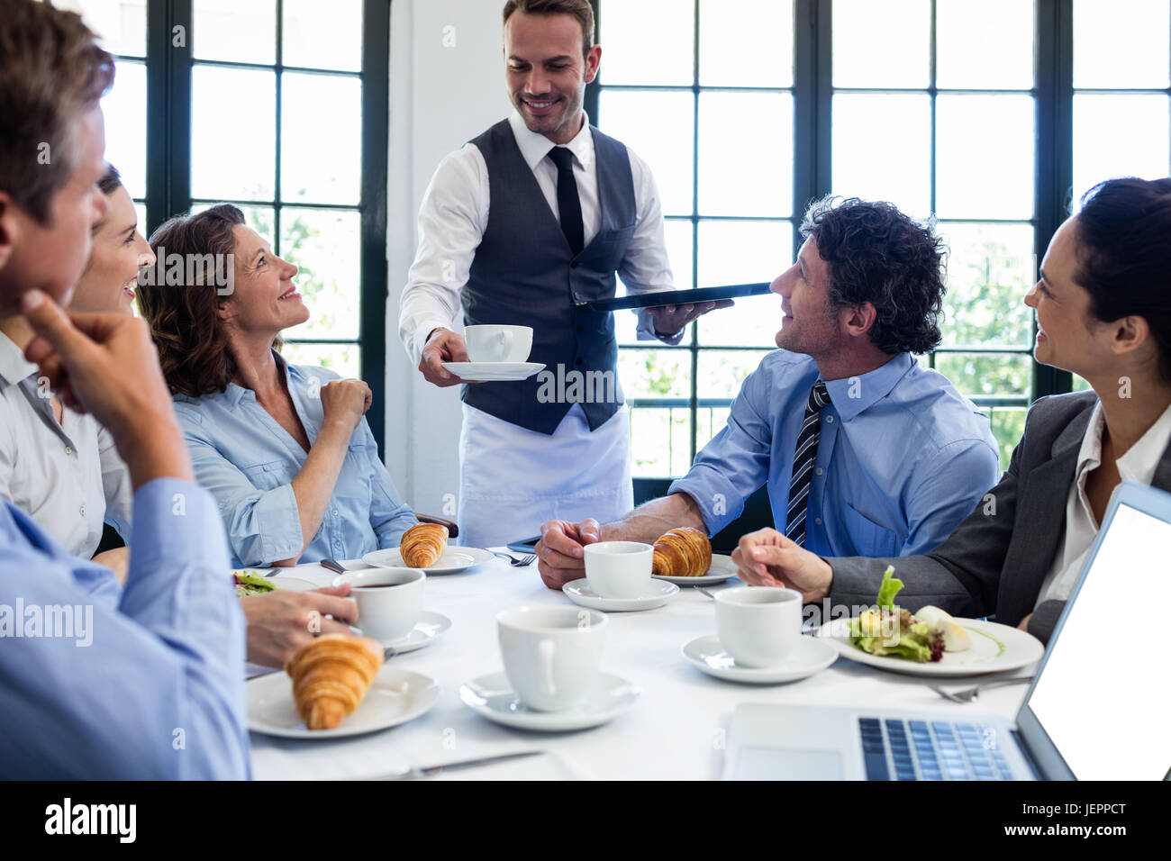 Waiter serving coffee to business people Stock Photo - Alamy