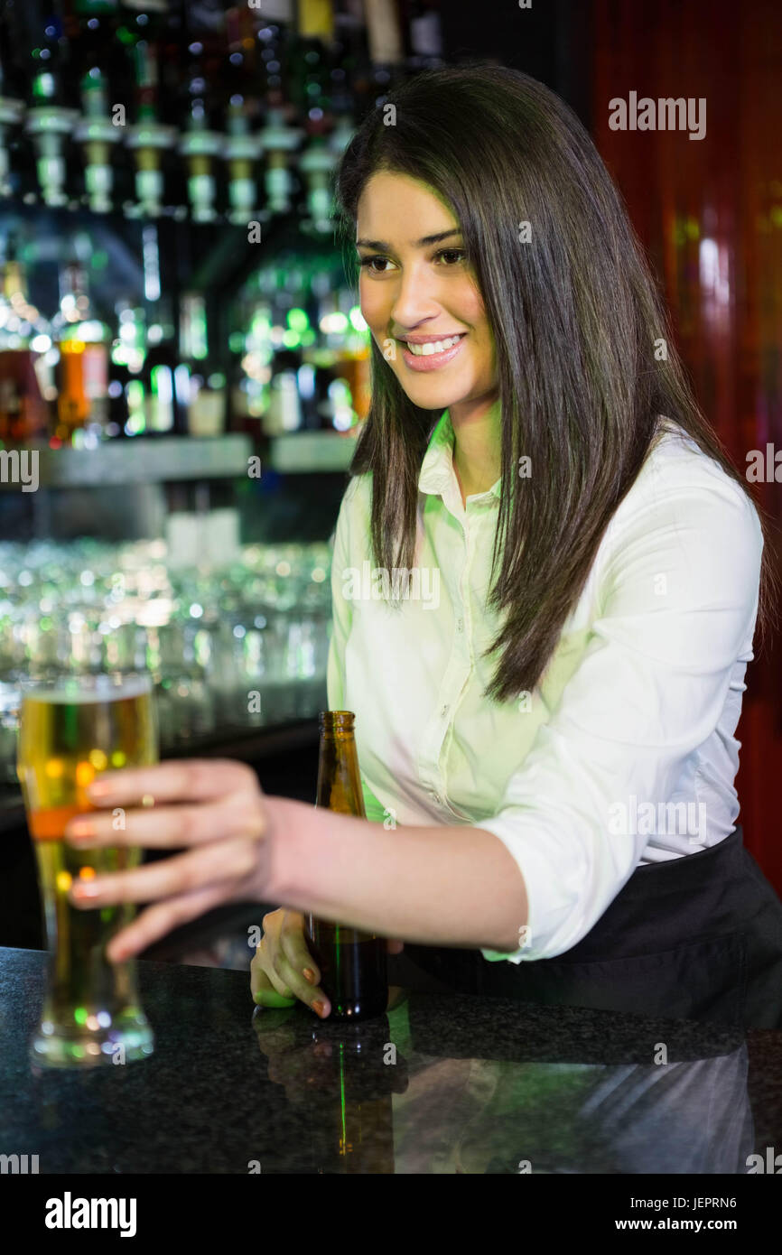 Pretty bartender serving beer at bar counter Stock Photo - Alamy