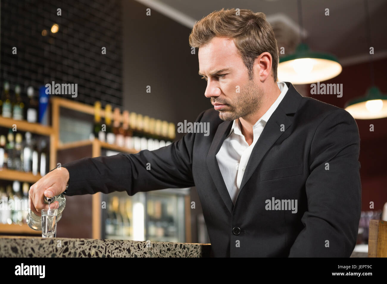 Tired man pouring a shot of alcohol Stock Photo - Alamy