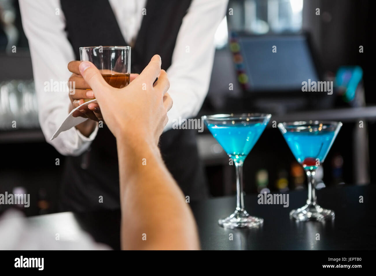Bartender serving whiskey at bar counter Stock Photo - Alamy