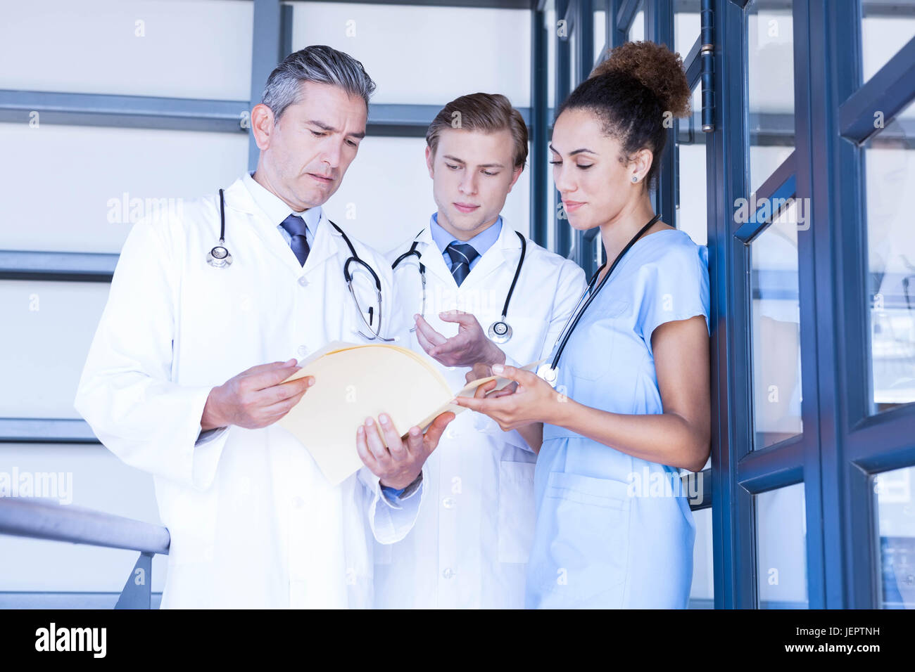 Doctors discussing medical report in corridor Stock Photo - Alamy