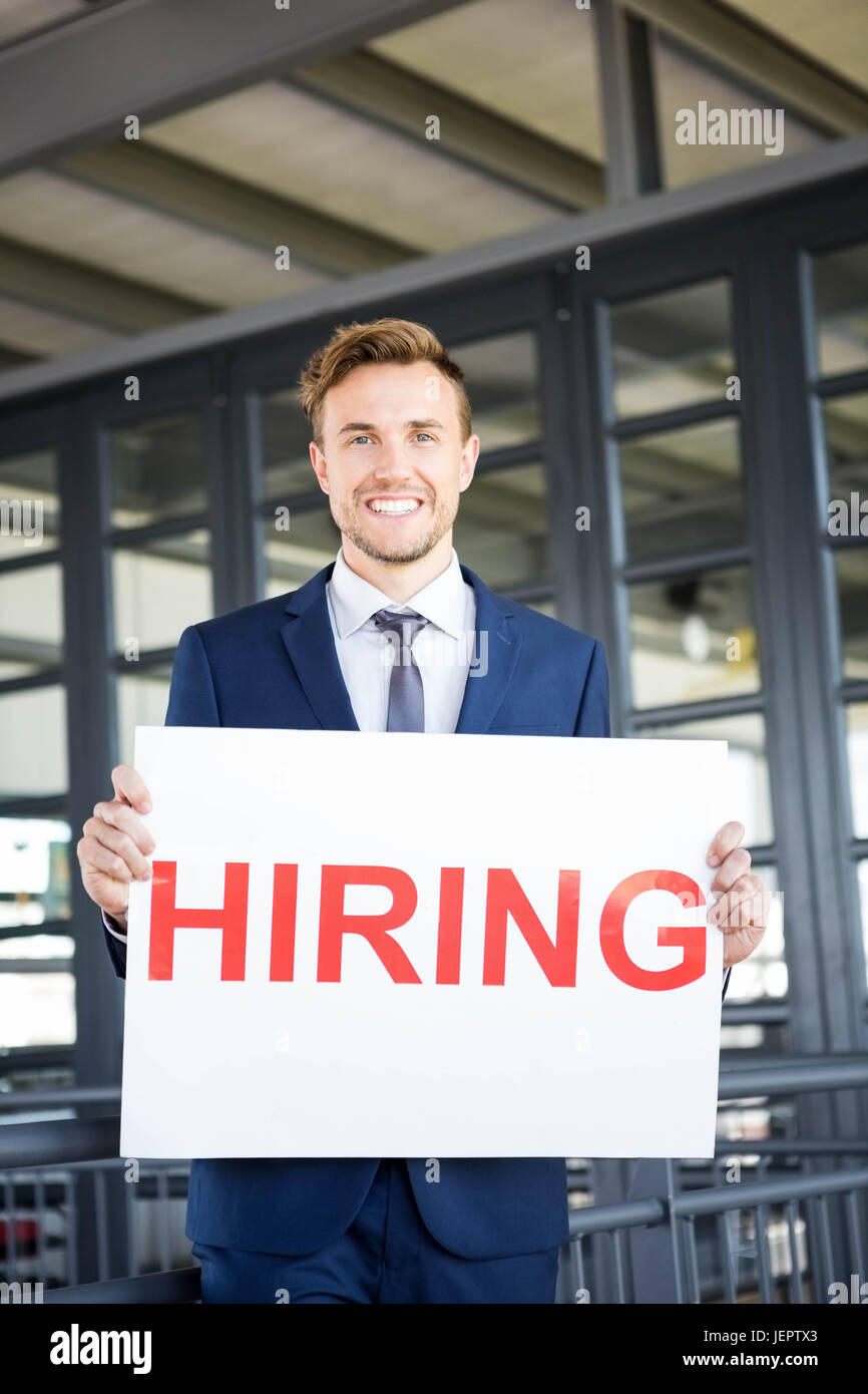 Businessman holding a hiring signboard Stock Photo - Alamy