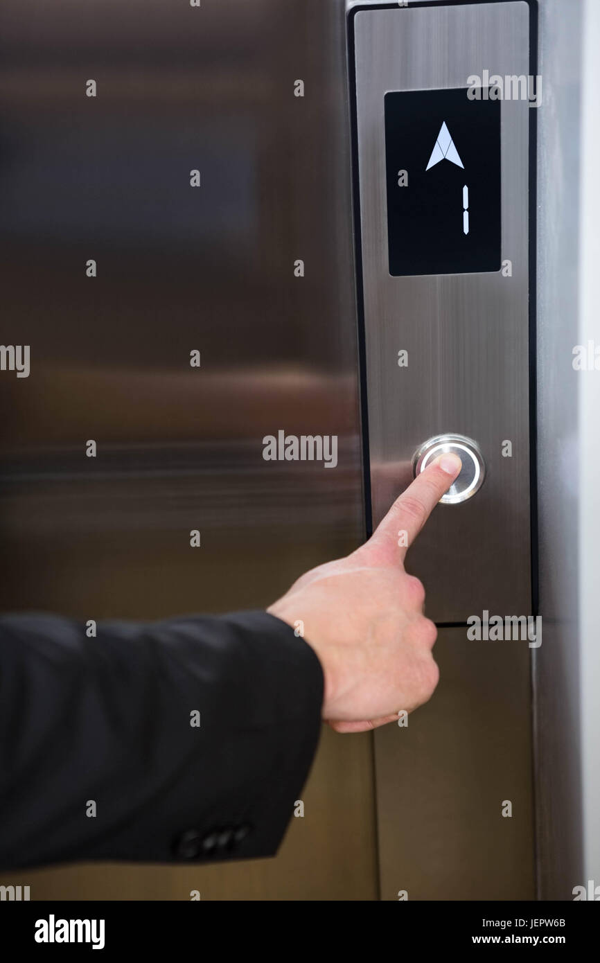 Businessman pressing elevator button Stock Photo - Alamy