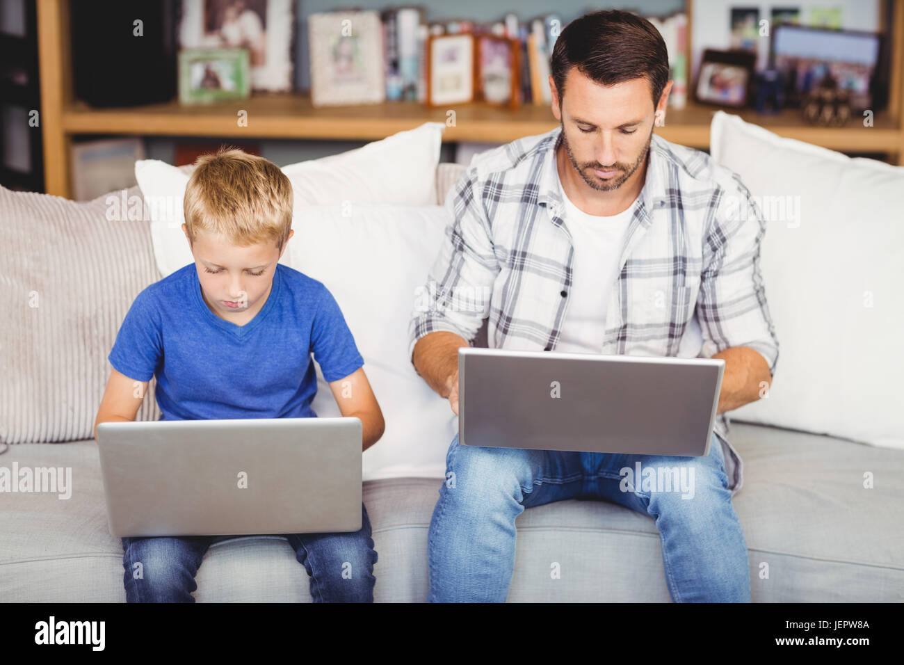 Father and son working on laptop at sofa Stock Photo - Alamy