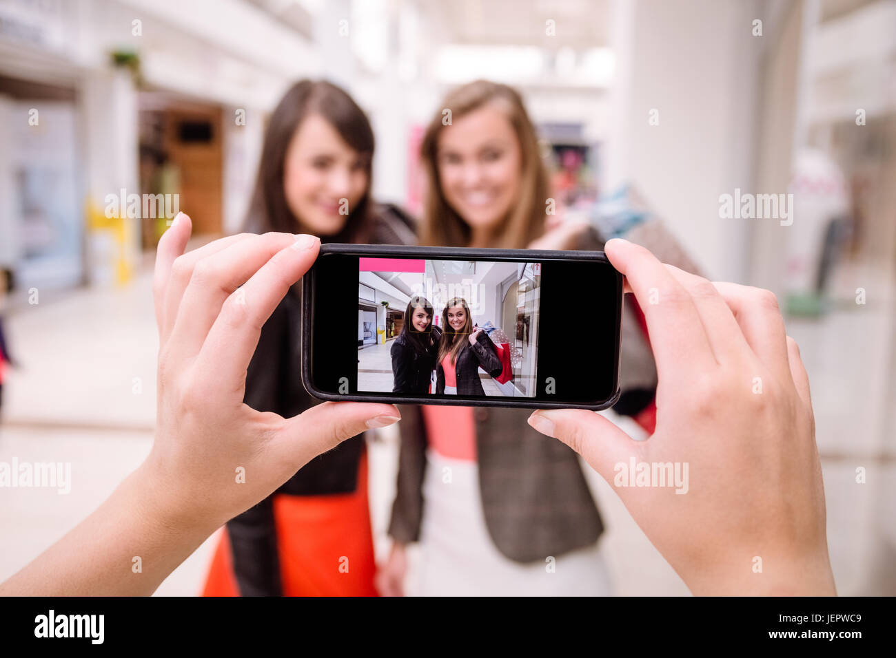 Two woman clicking a photo in phone Stock Photo - Alamy