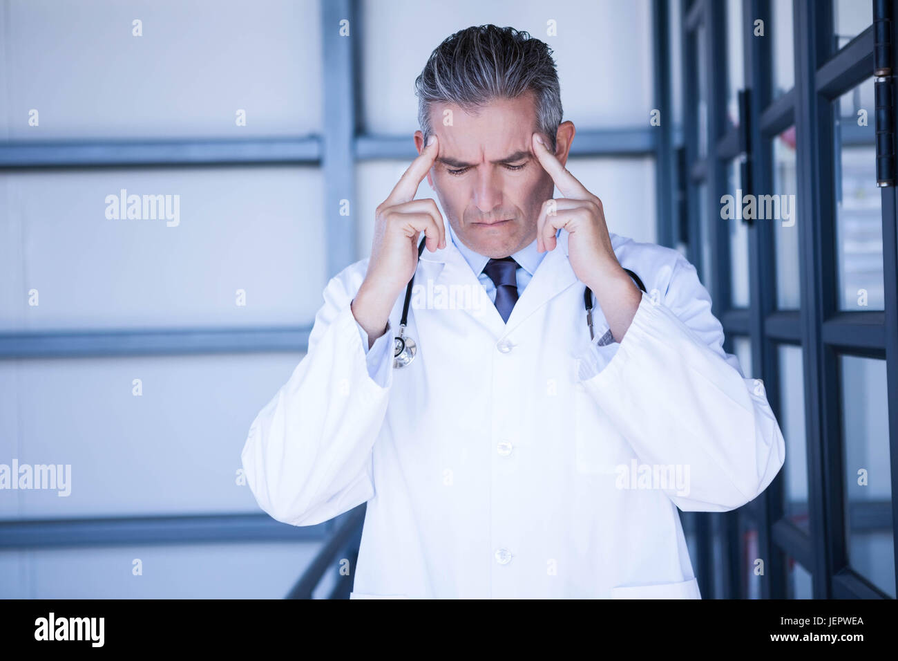 Thoughtful doctor standing in hospital Stock Photo - Alamy