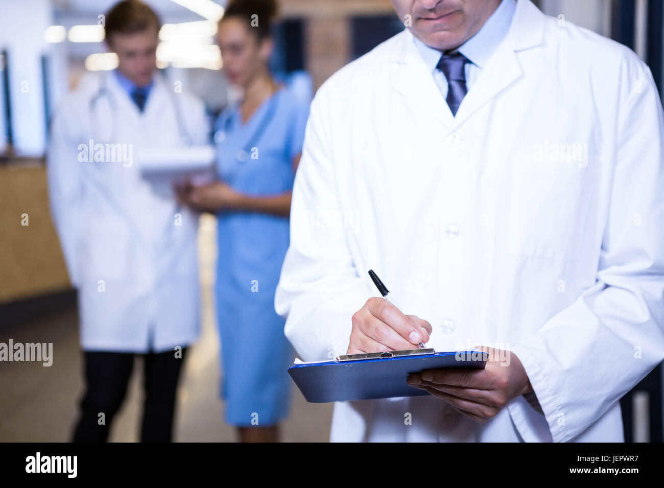 Male doctor writing on clipboard Stock Photo - Alamy