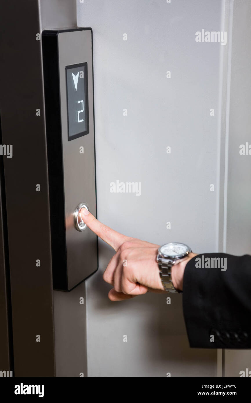 Businessman pressing elevator button Stock Photo - Alamy