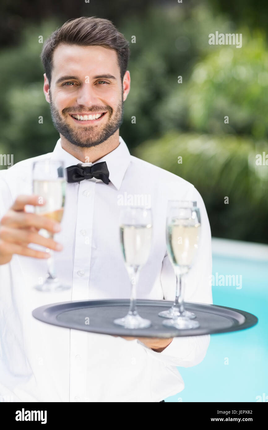 Happy waiter offering champagne Stock Photo - Alamy