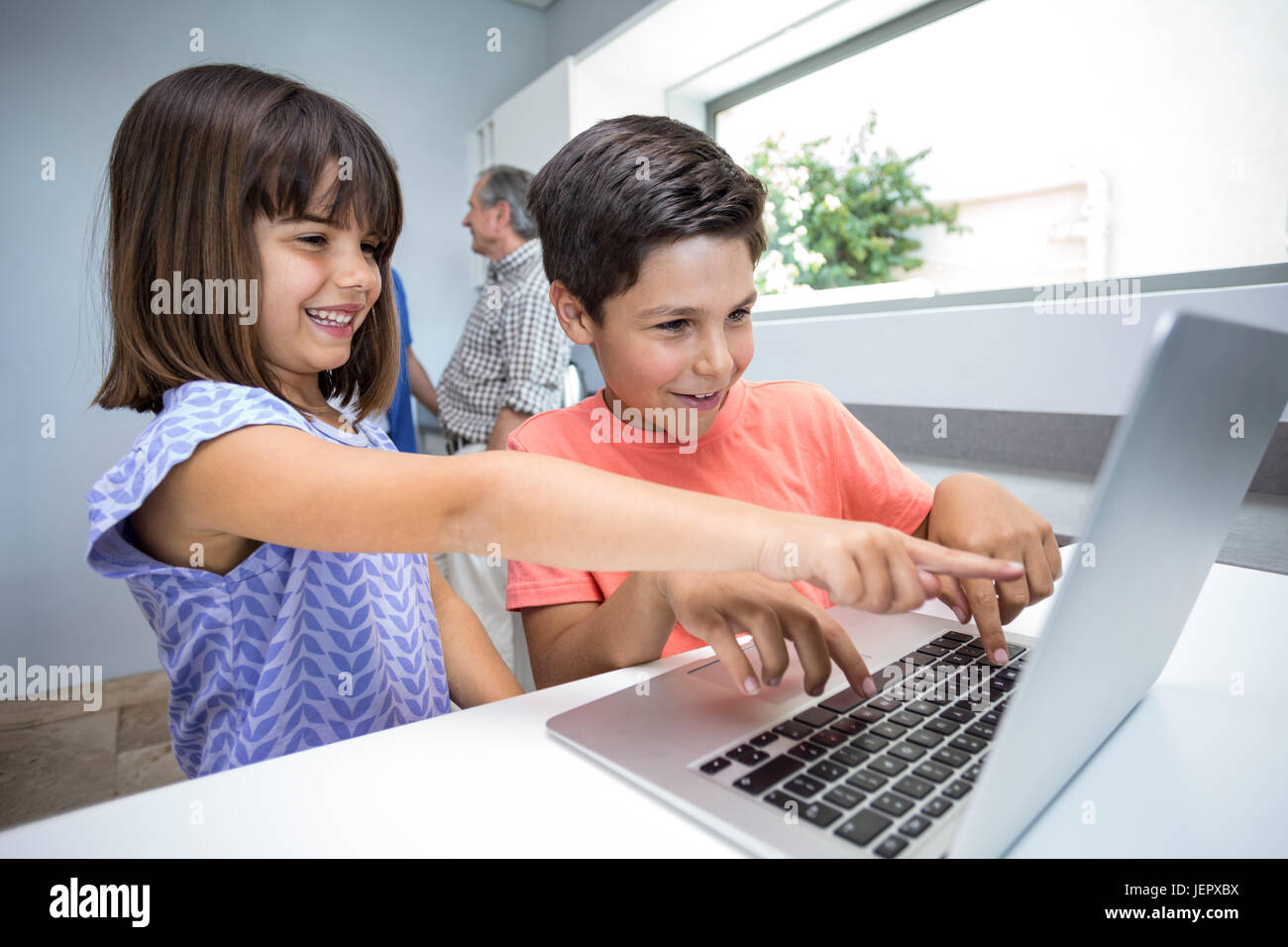 Happy boy and girl using laptop Stock Photo - Alamy