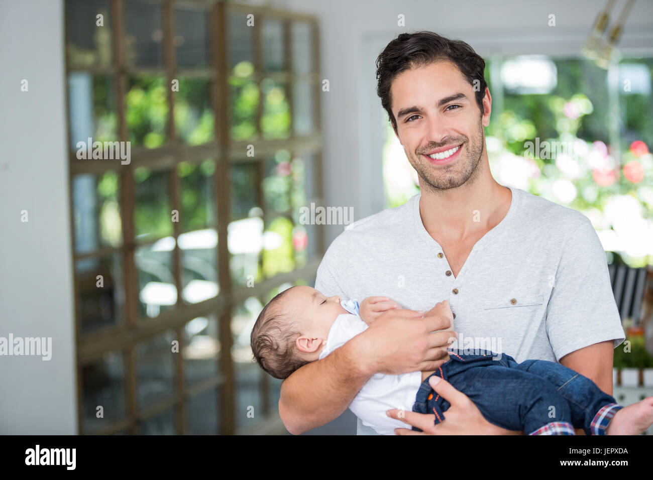 Portrait of smiling father carrying baby Stock Photo - Alamy