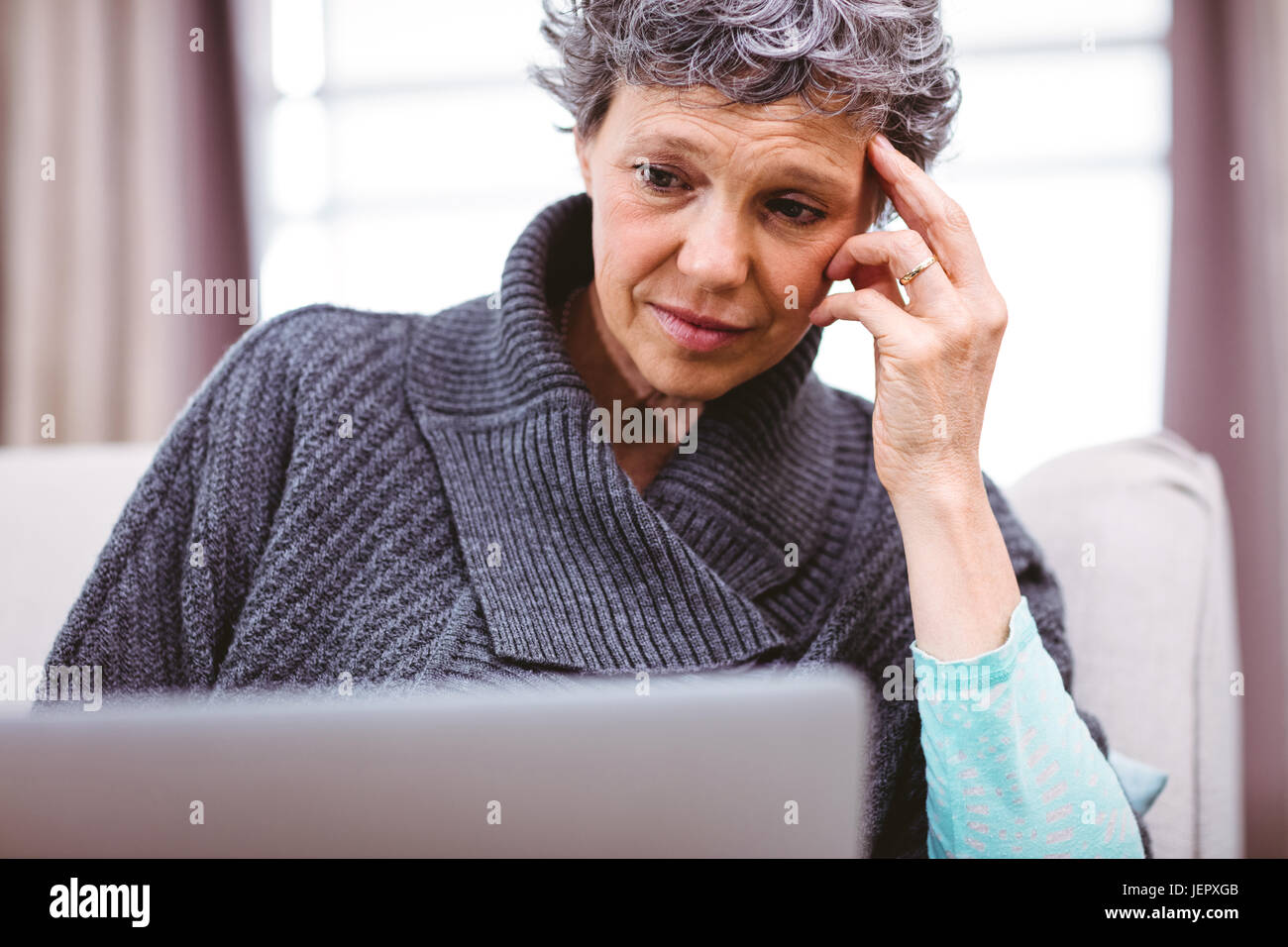 Mature woman thinking while using laptop Stock Photo - Alamy