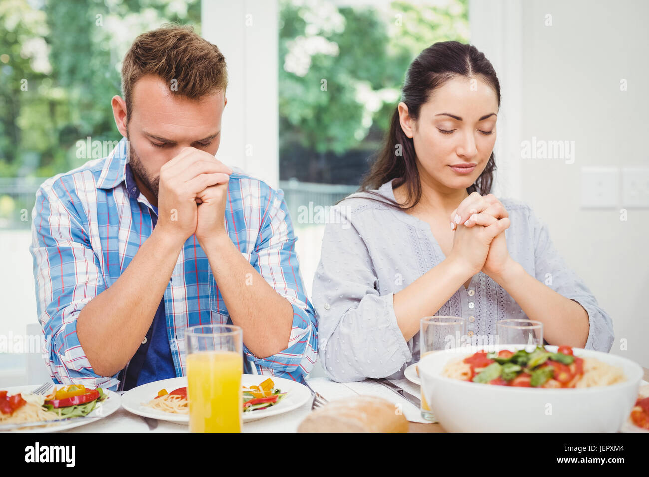 Couple praying while sitting at dining table Stock Photo - Alamy