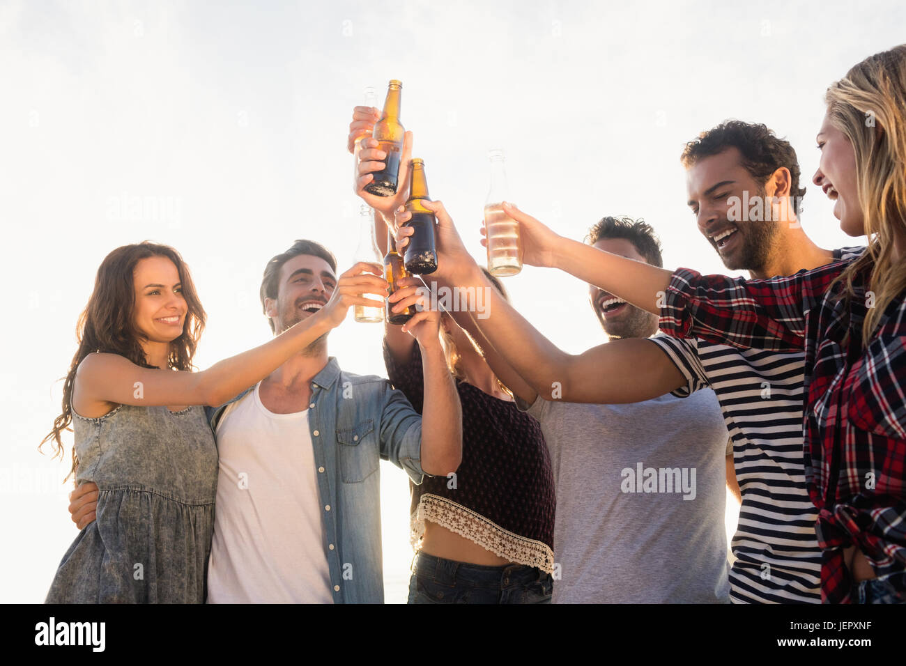 Happy friends raising beer bottles Stock Photo - Alamy