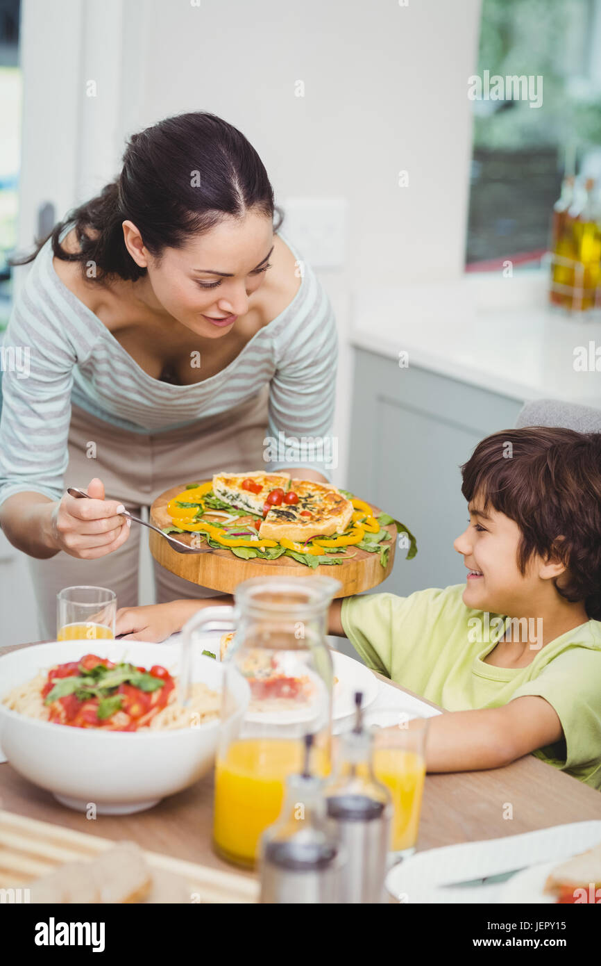 Mother serving food to son Stock Photo - Alamy