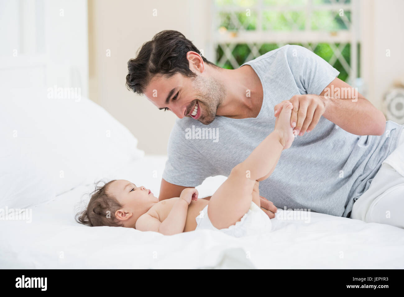 Smiling father playing with baby on bed Stock Photo - Alamy
