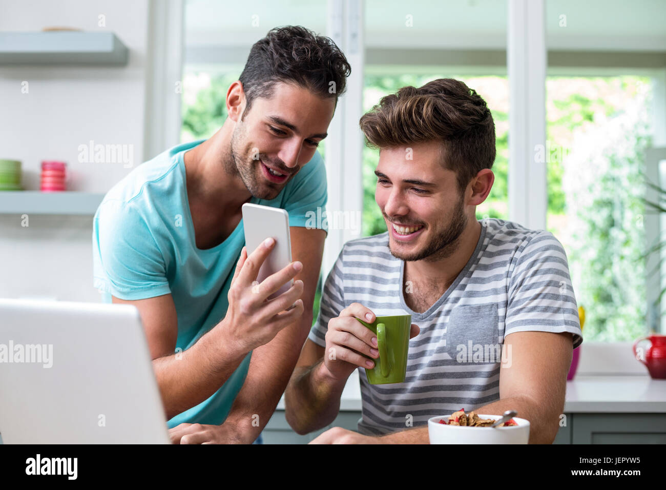 Smiling man showing phone to friend Stock Photo - Alamy