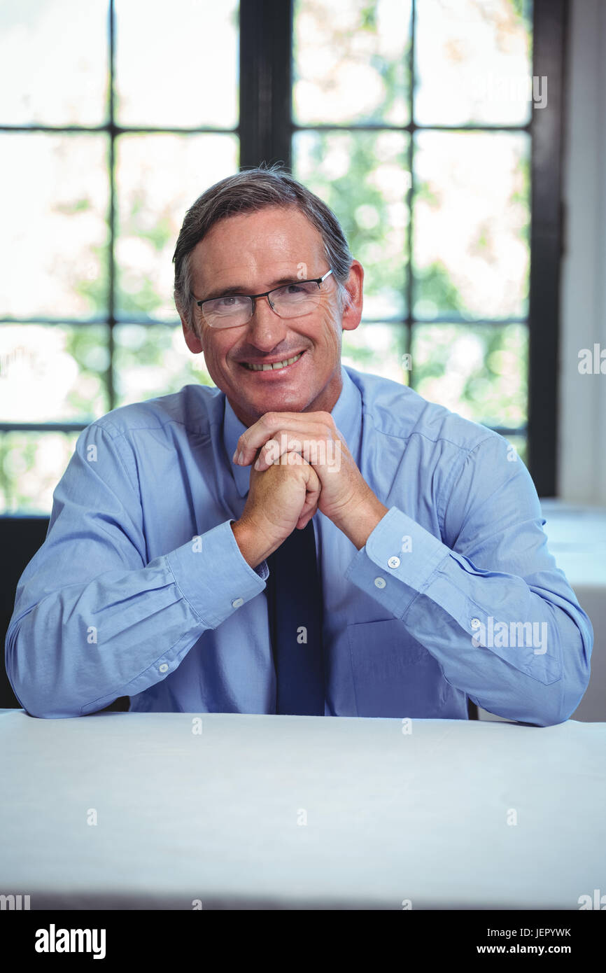 Smiling businessman leaning on a table Stock Photo - Alamy