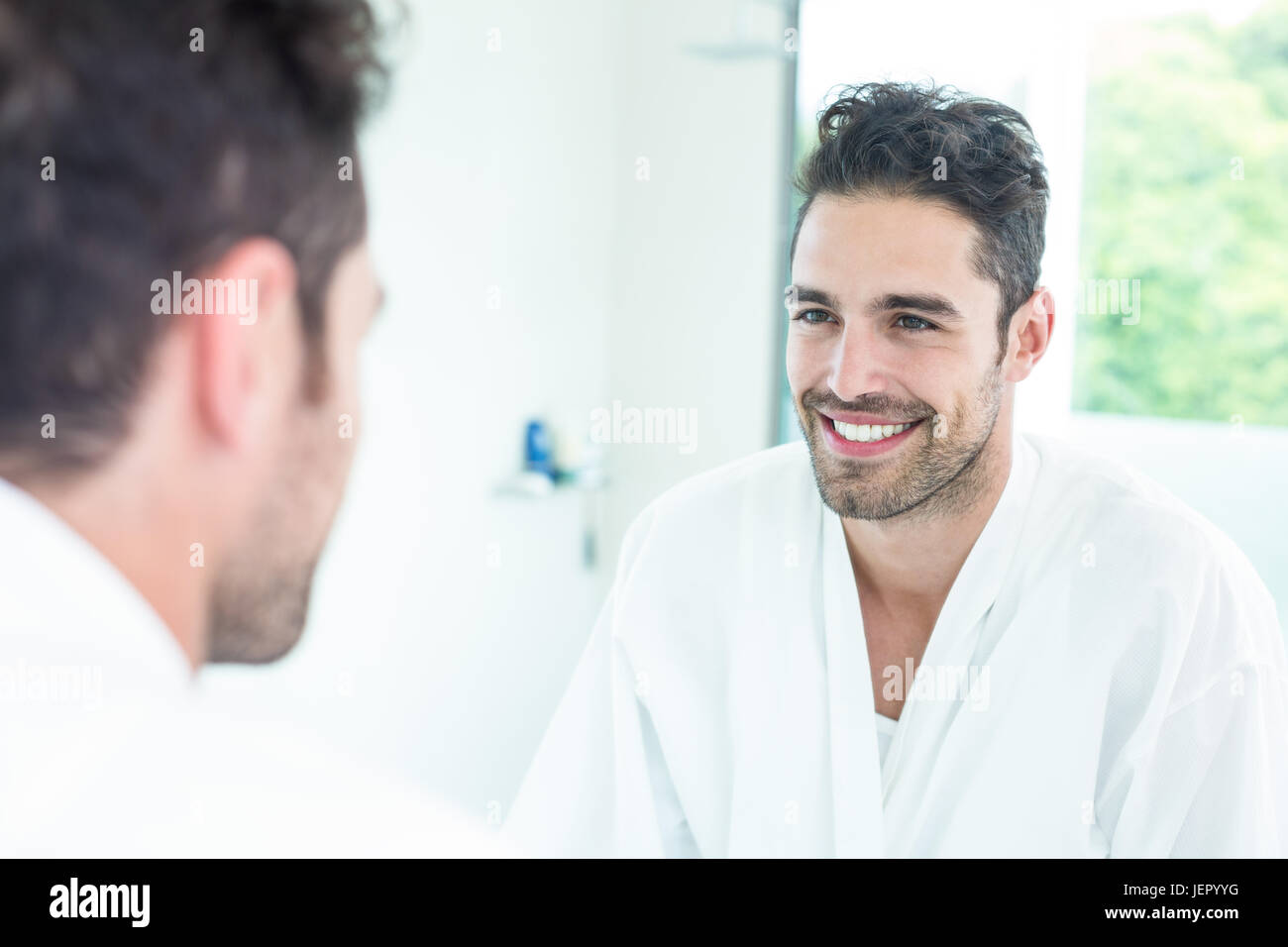 Handsome man looking in mirror Stock Photo - Alamy