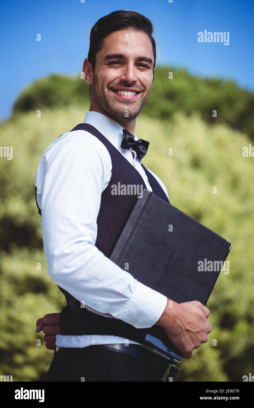 Handsome waiter holding menus Stock Photo - Alamy
