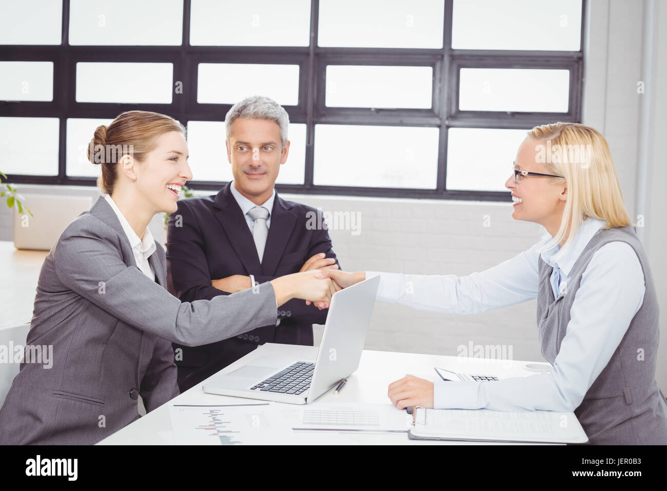 Happy business people handshaking with client Stock Photo - Alamy