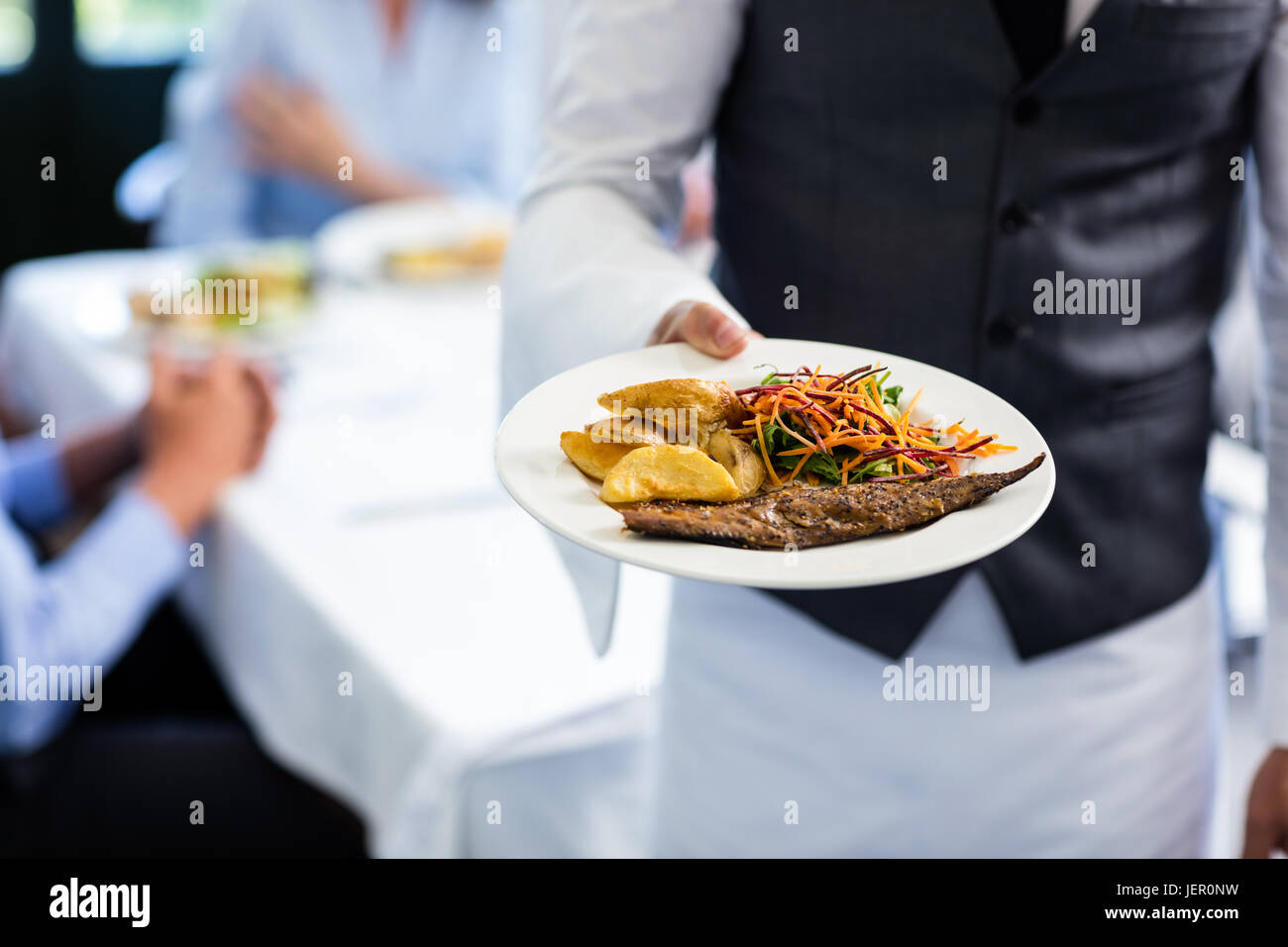 Waiter holding a plate of meal Stock Photo - Alamy