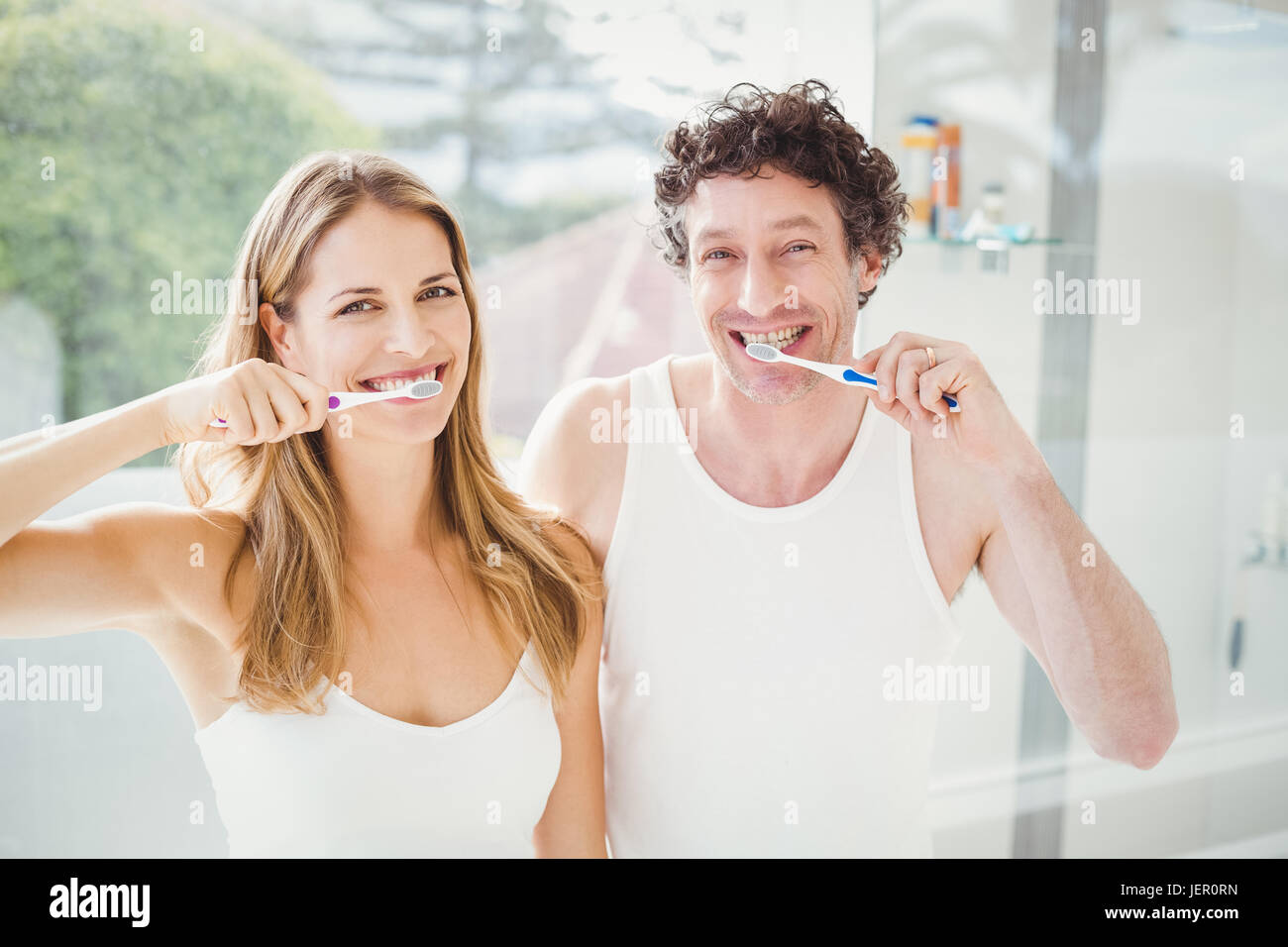 Happy couple brushing teeth Stock Photo - Alamy