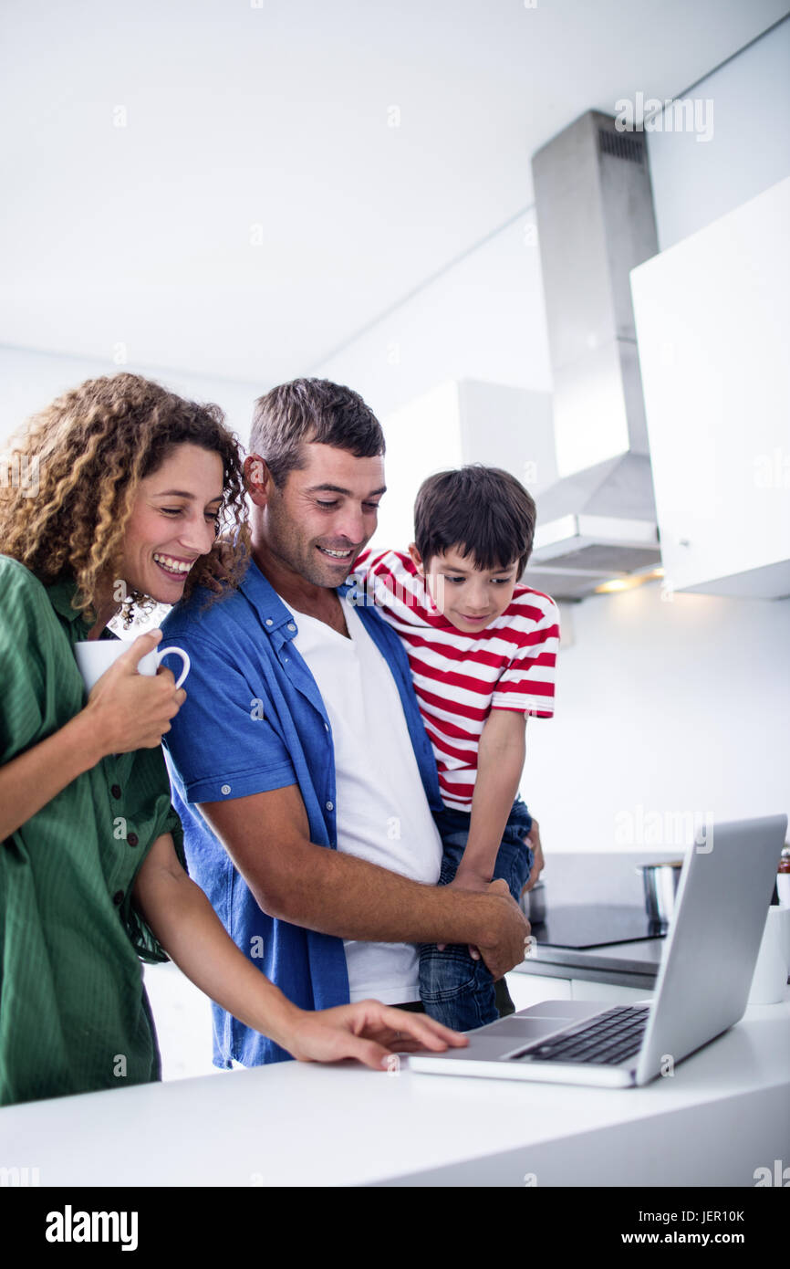 Parents using laptop with son in kitchen Stock Photo - Alamy