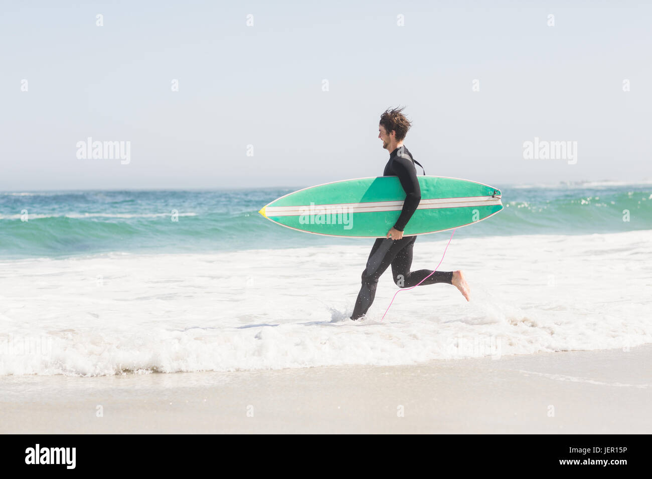 Man with surfboard running towards sea Stock Photo - Alamy