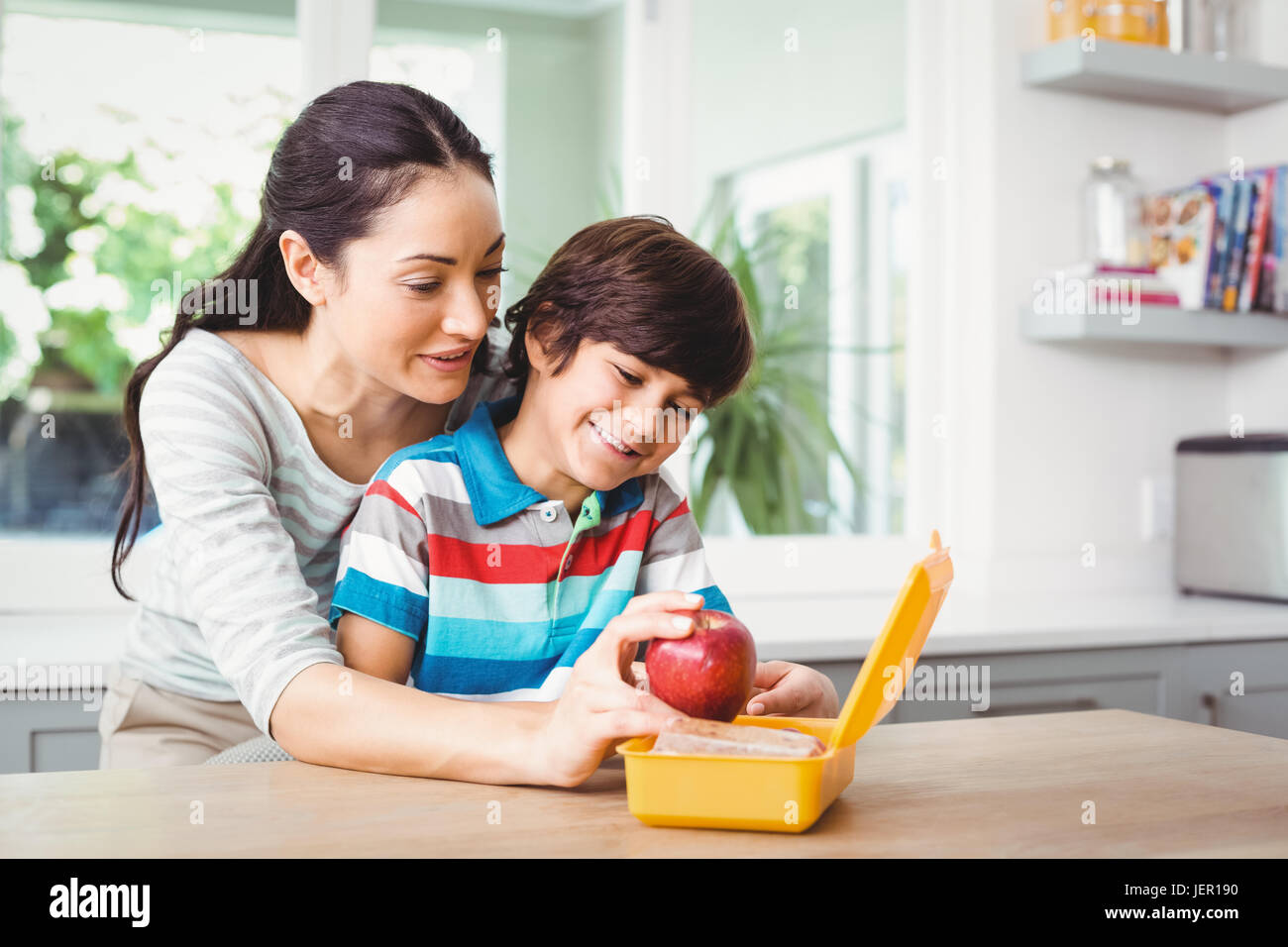 Smiling mother holding apple with son Stock Photo - Alamy