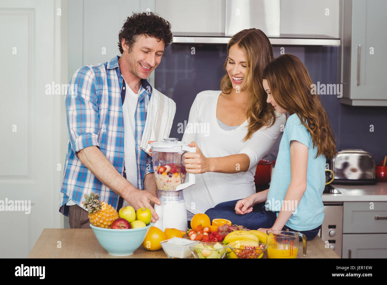 Parents and daughter preparing fruit juice Stock Photo - Alamy