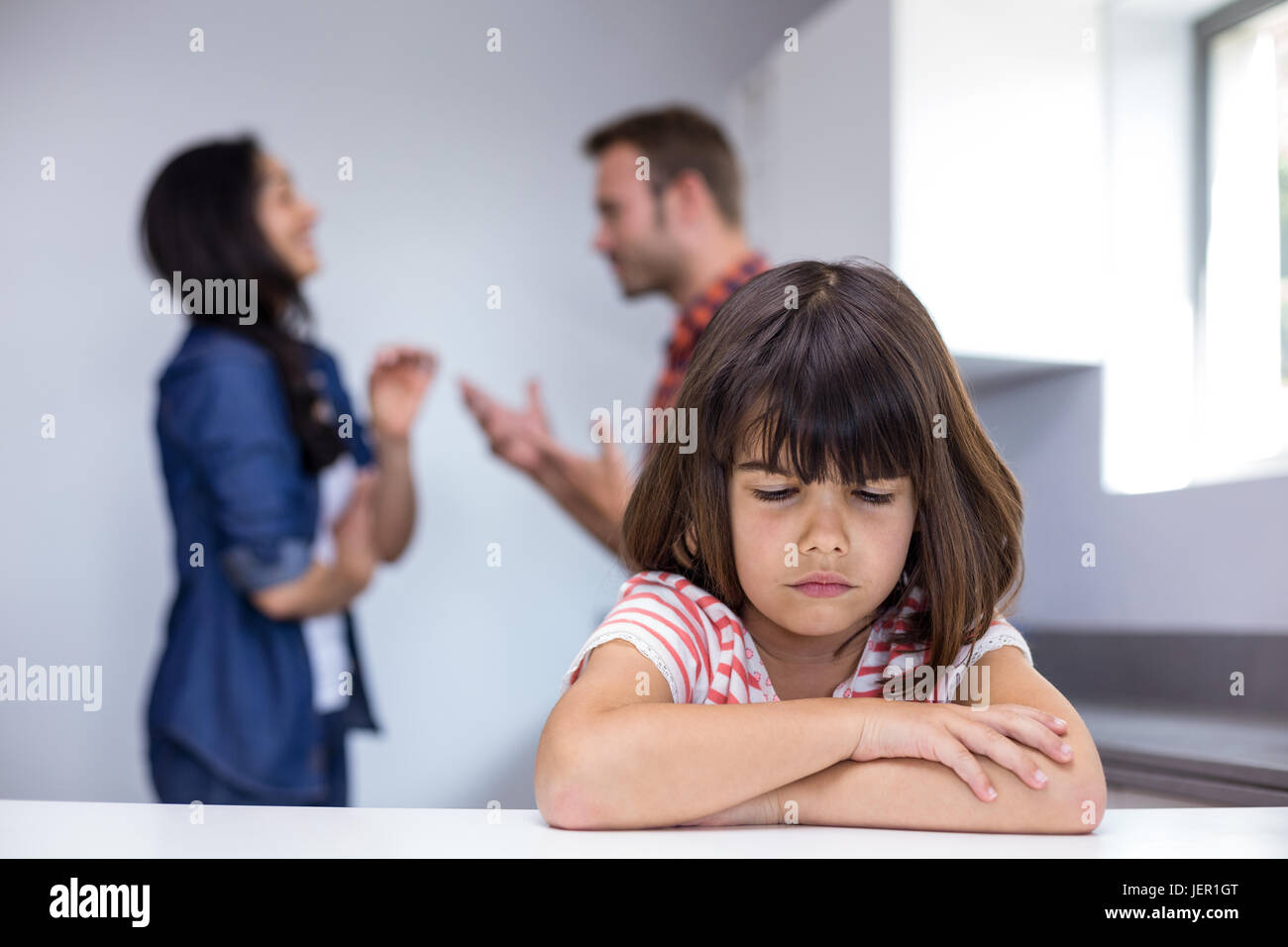 Sad girl hearing her parents arguing Stock Photo - Alamy