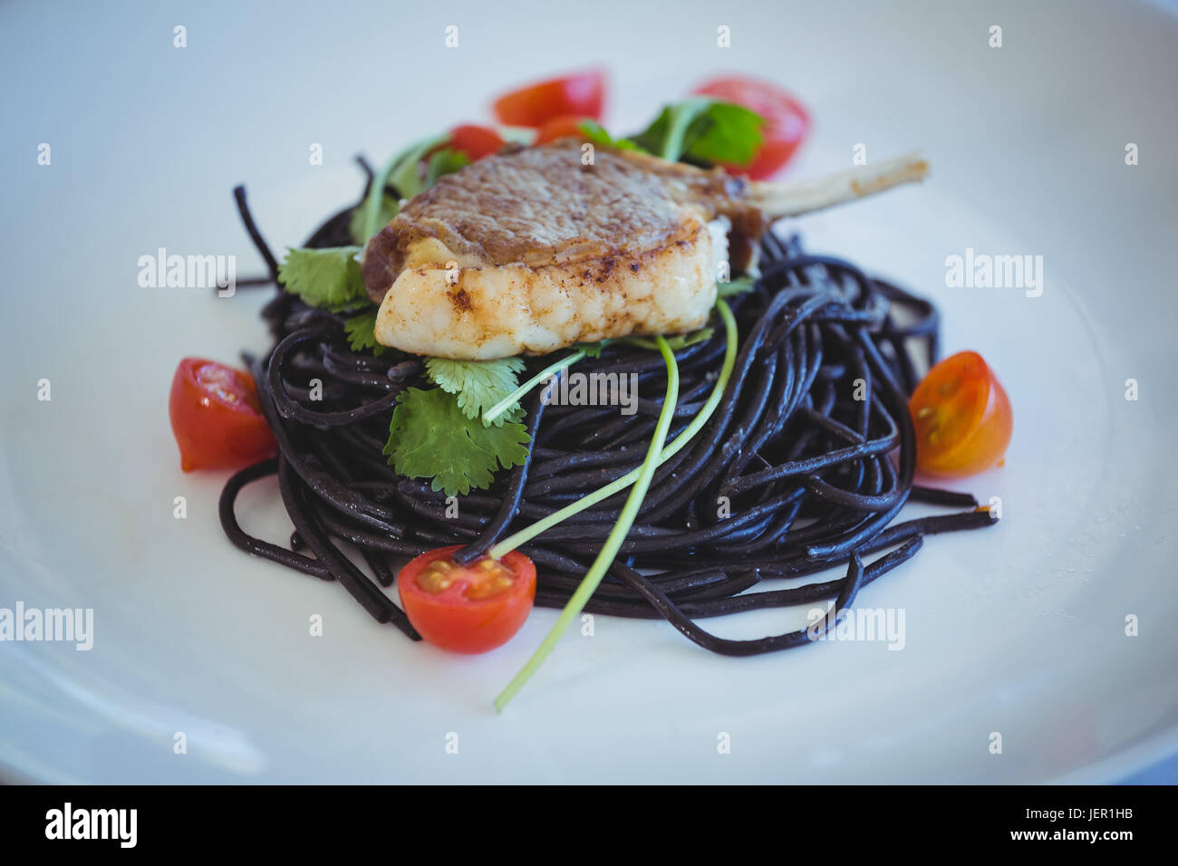 Squid ink spaghetti dish with basil Stock Photo - Alamy