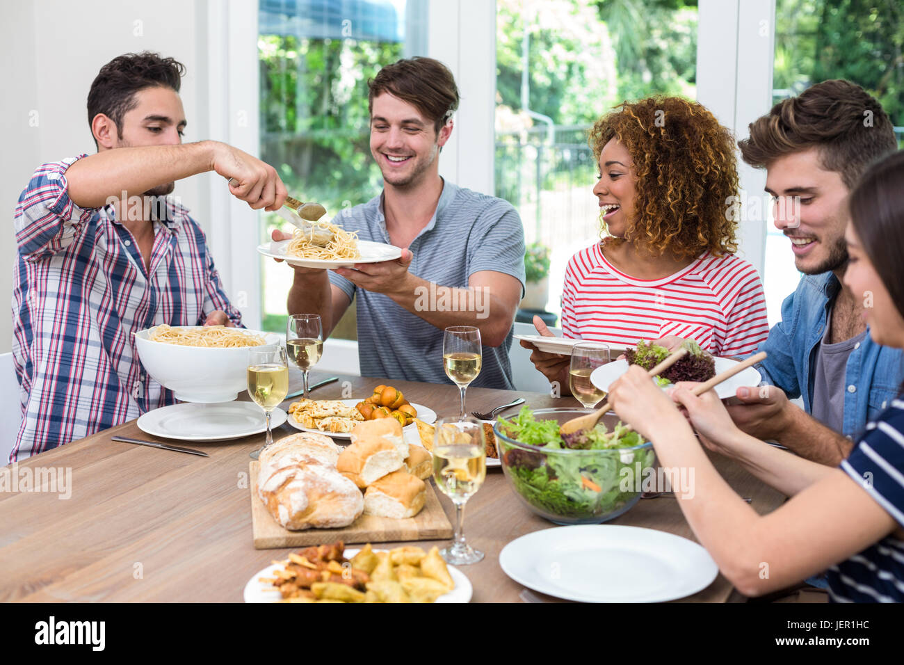 Friends having meal at table in house Stock Photo - Alamy