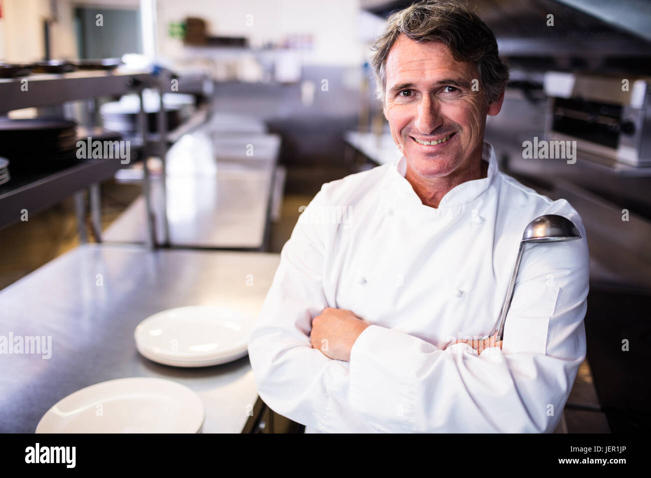 Smiling chef holding ladle in the kitchen Stock Photo - Alamy