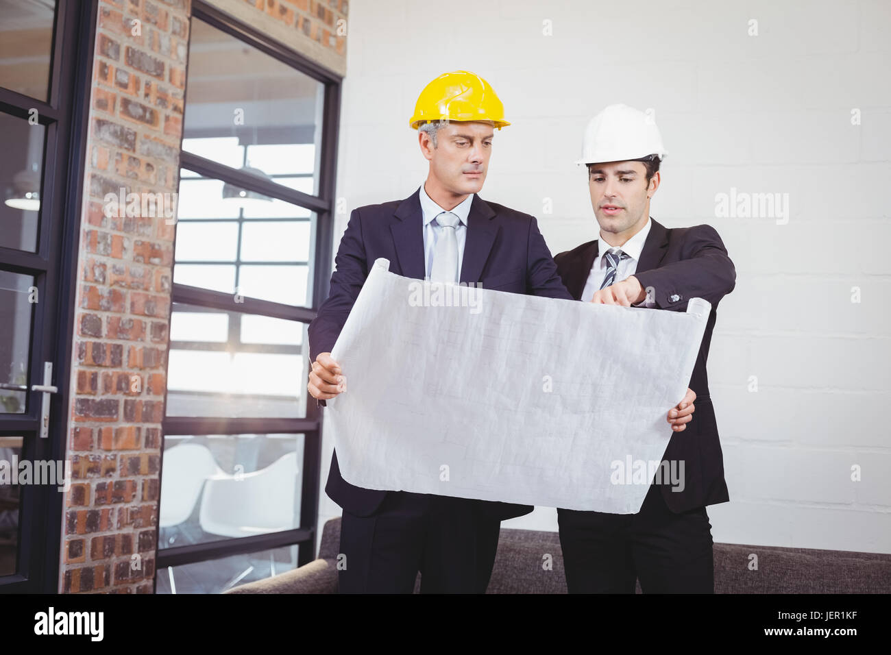 Architects holding blueprint Stock Photo - Alamy