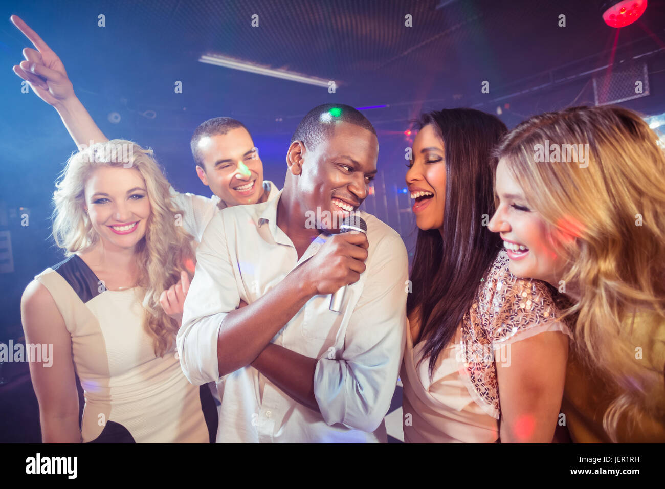 Happy friends singing at the karaoke Stock Photo - Alamy
